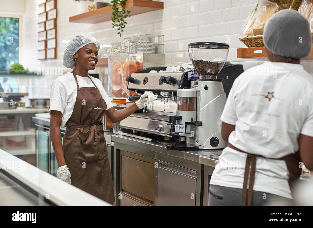 Young woman working in ice cream parlour, operating coffee machine ...