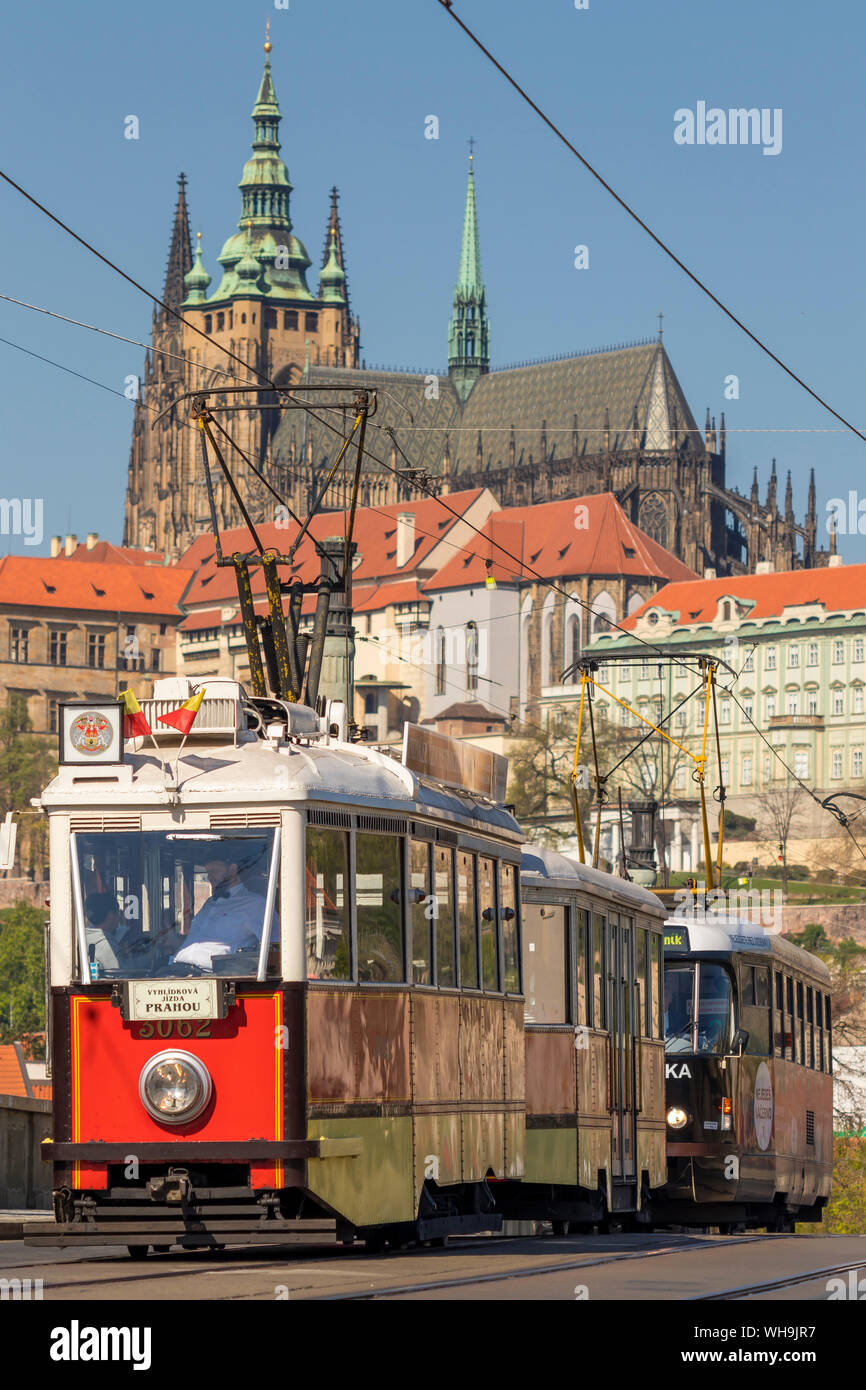 Tourist tram passing a bridge over Vltava River with view to Prague ...