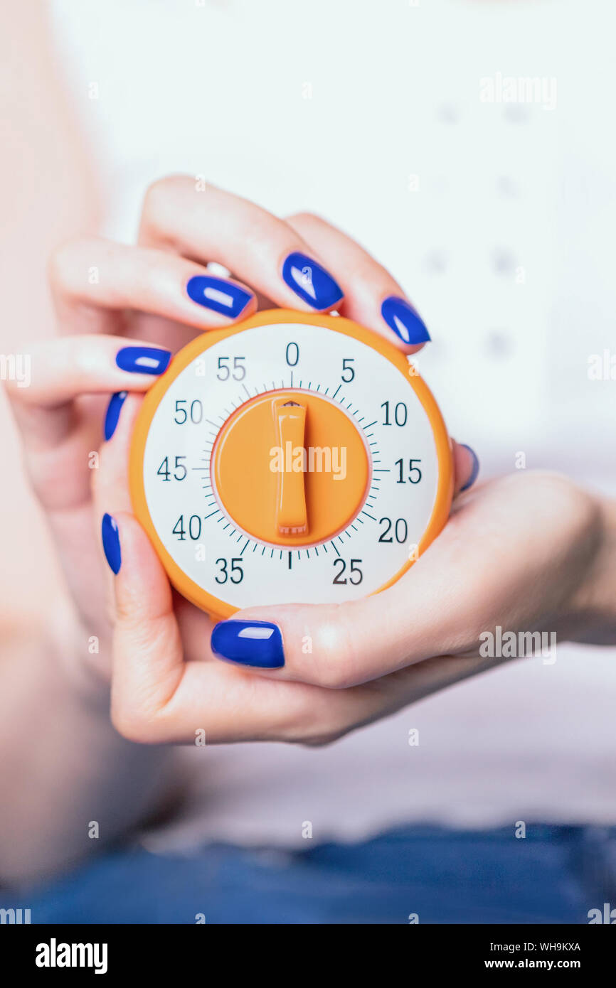 Female hands with blue manicure holding kitchen timer on a light ...