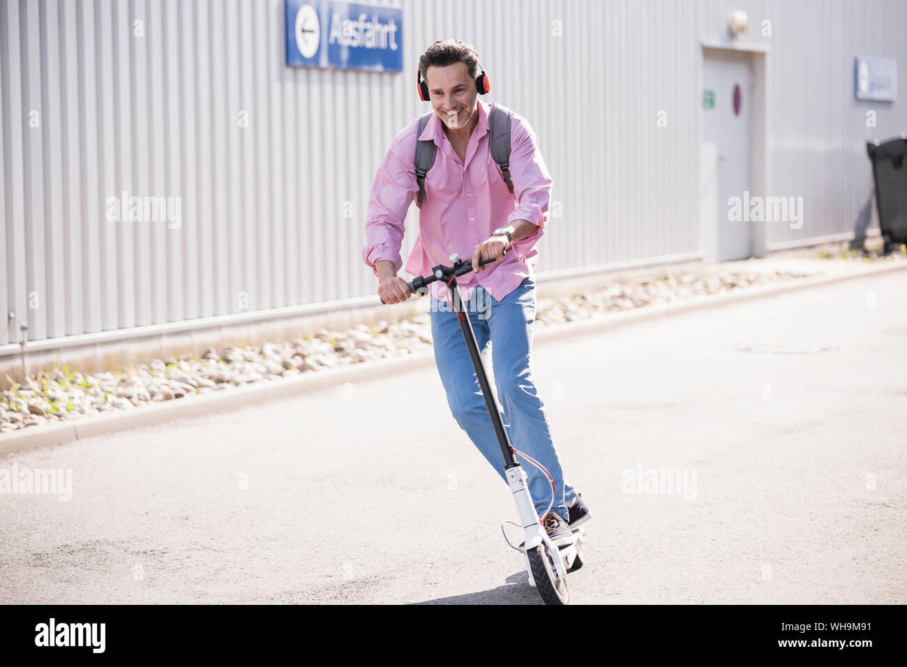 Businessman with backpack riding his E-Scooter Stock Photo - Alamy