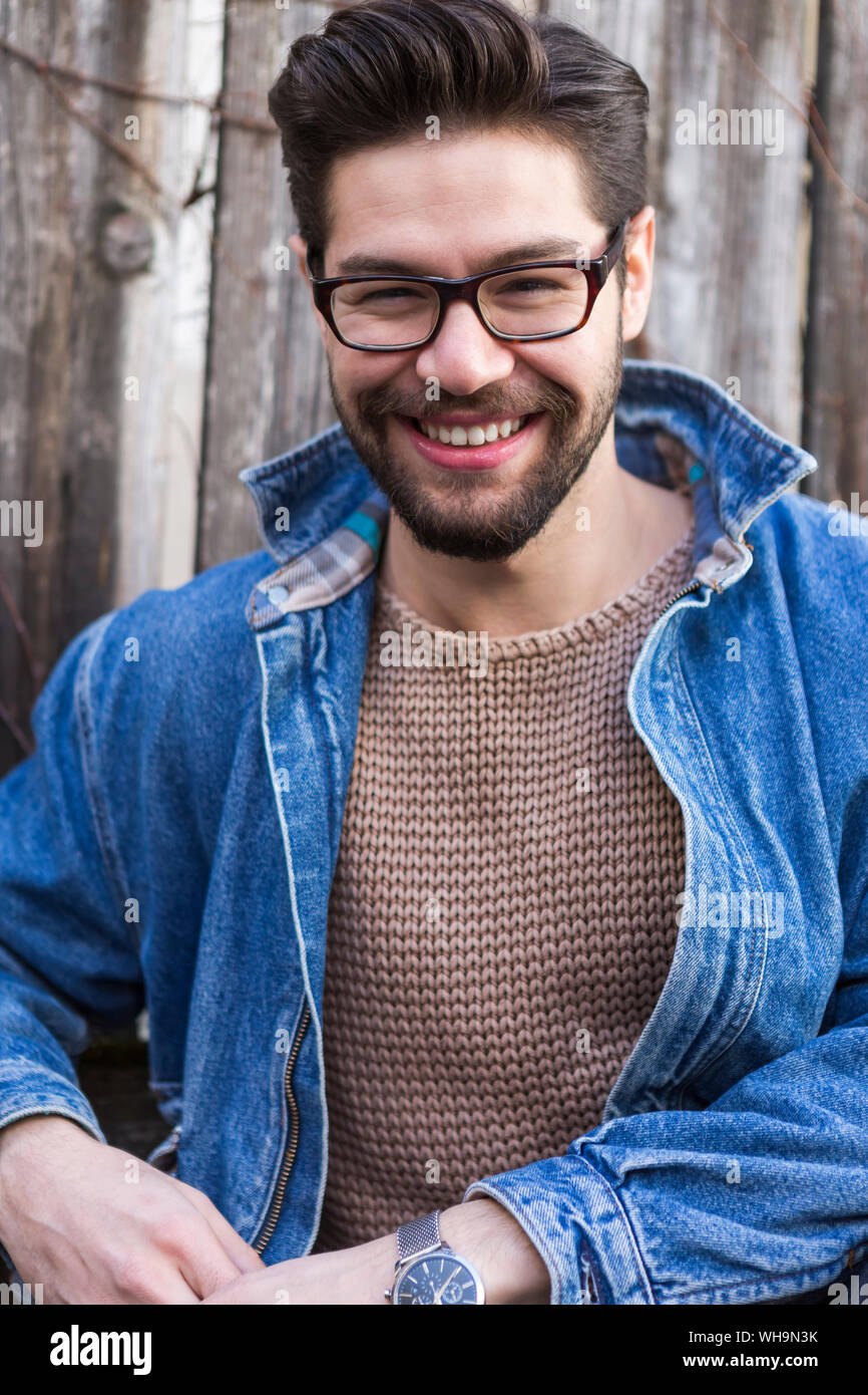 Portrait of laughing young man wearing glasses and denim jacket Stock ...
