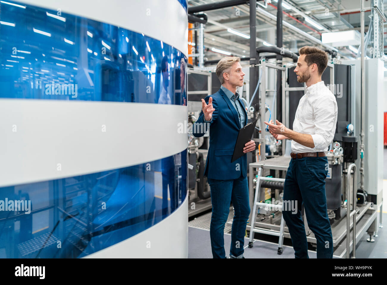 Two businessmen talking in a modern factory Stock Photo - Alamy