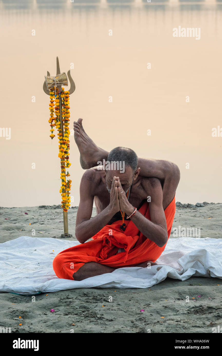 Sadhu practising yoga at sunrise on Ganges riverbank, Allahabad Kumbh ...