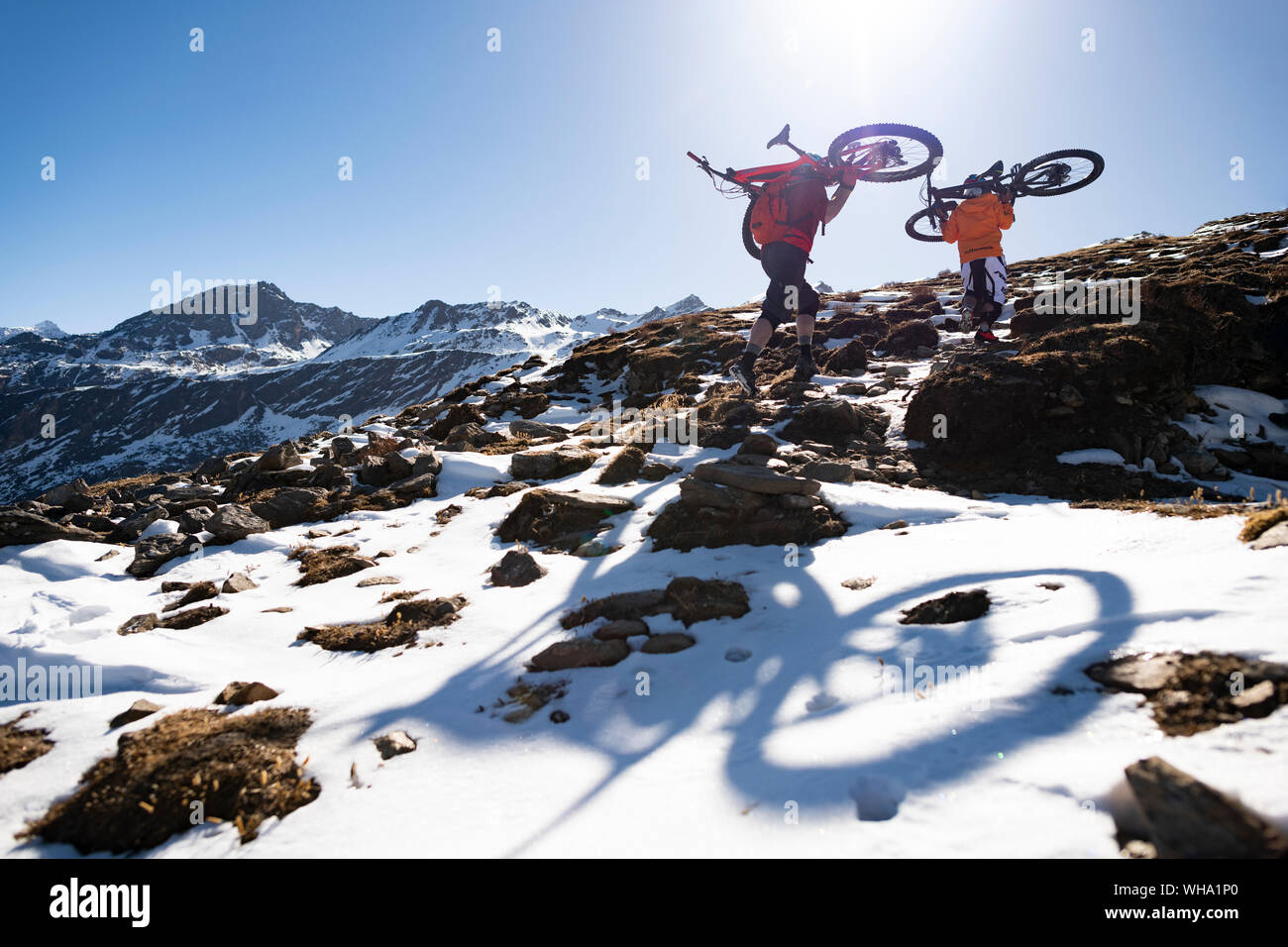 Mountain bikers carry their bikes up a snow covered hillside in the ...