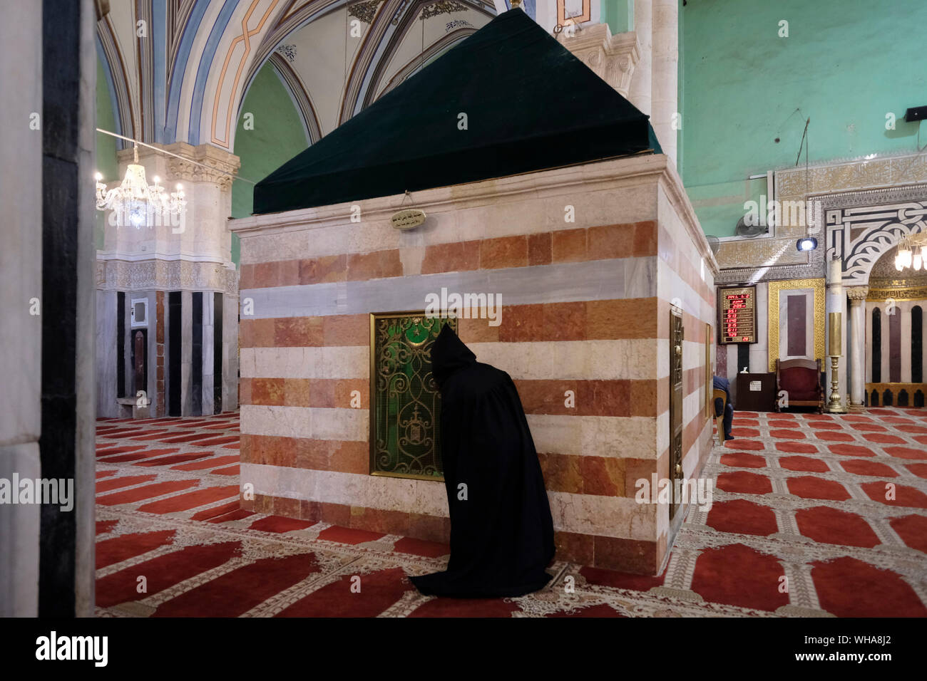A woman wearing full body robe looks inside the dome like structure ...