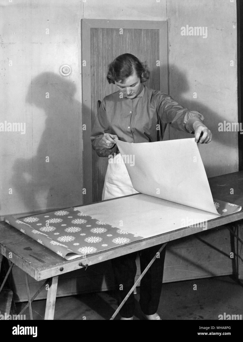 Woman decorating hanging wallpaper. Correct folding of pasted paper to ...