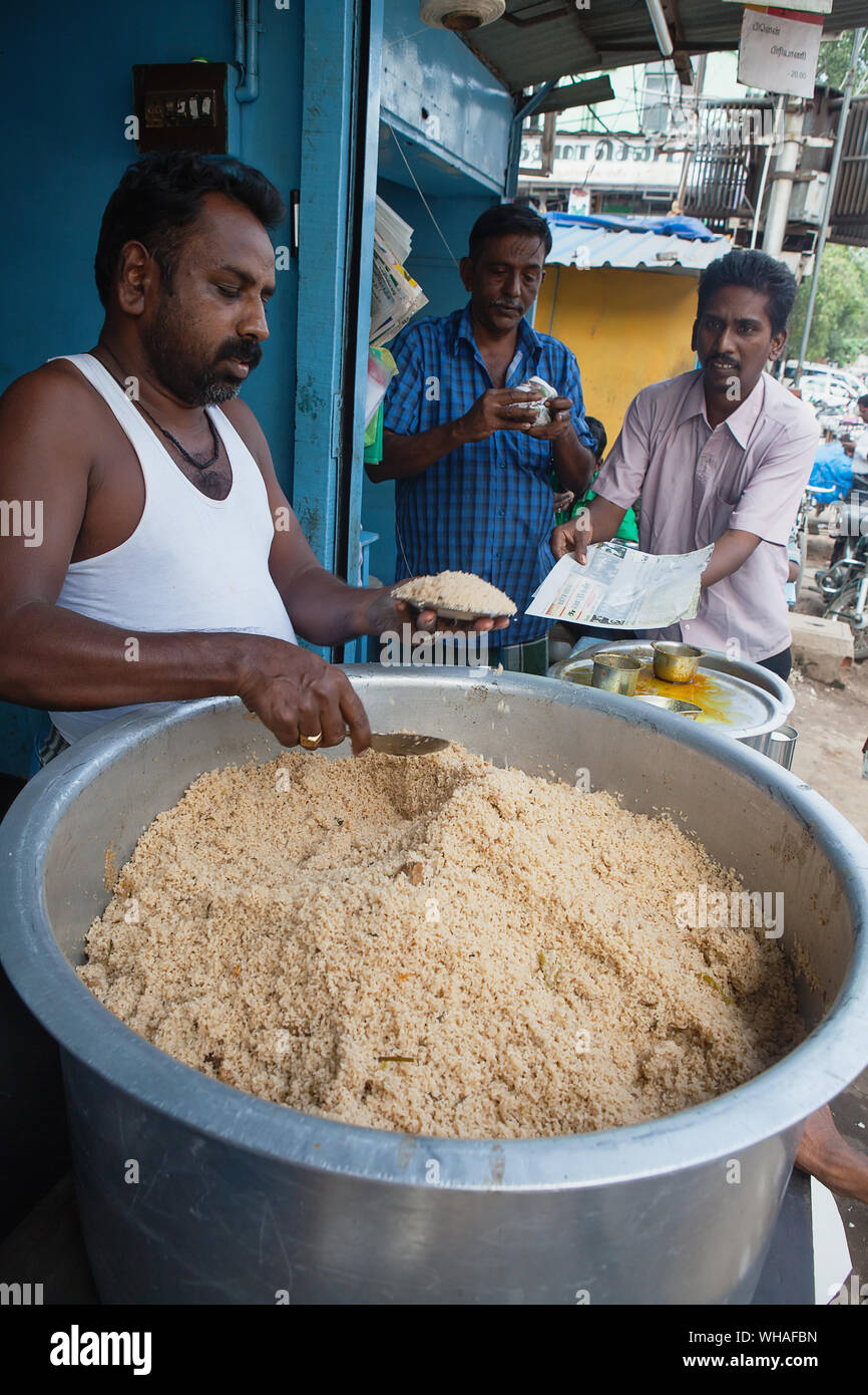 India, Tamil Nadu, Madurai, Cook serving portions of rice biryani at a ...