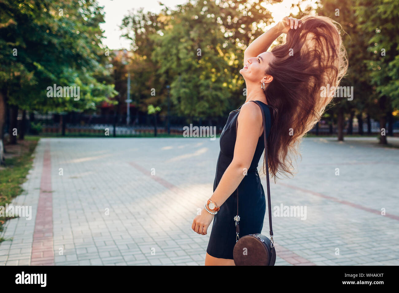 Young beautiful woman walking in summer park. Stylish lady throwing her ...