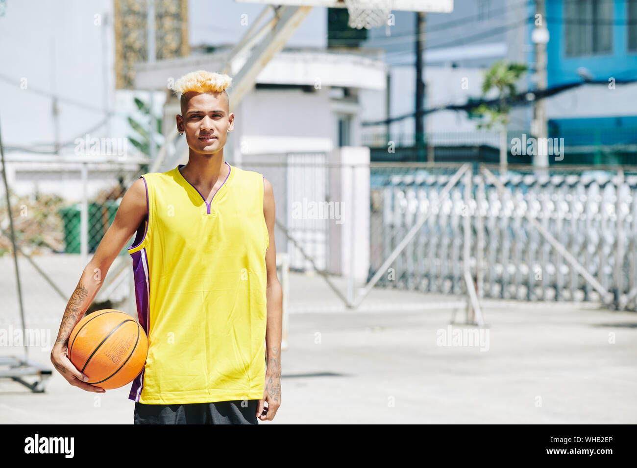 Portrait of Black handsome basketball player in bright yellow top ...