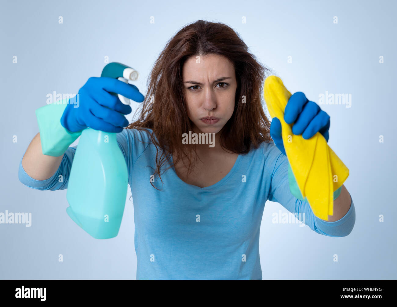 Angry and upset woman with cleaning spray and cloth cleaning feeling ...
