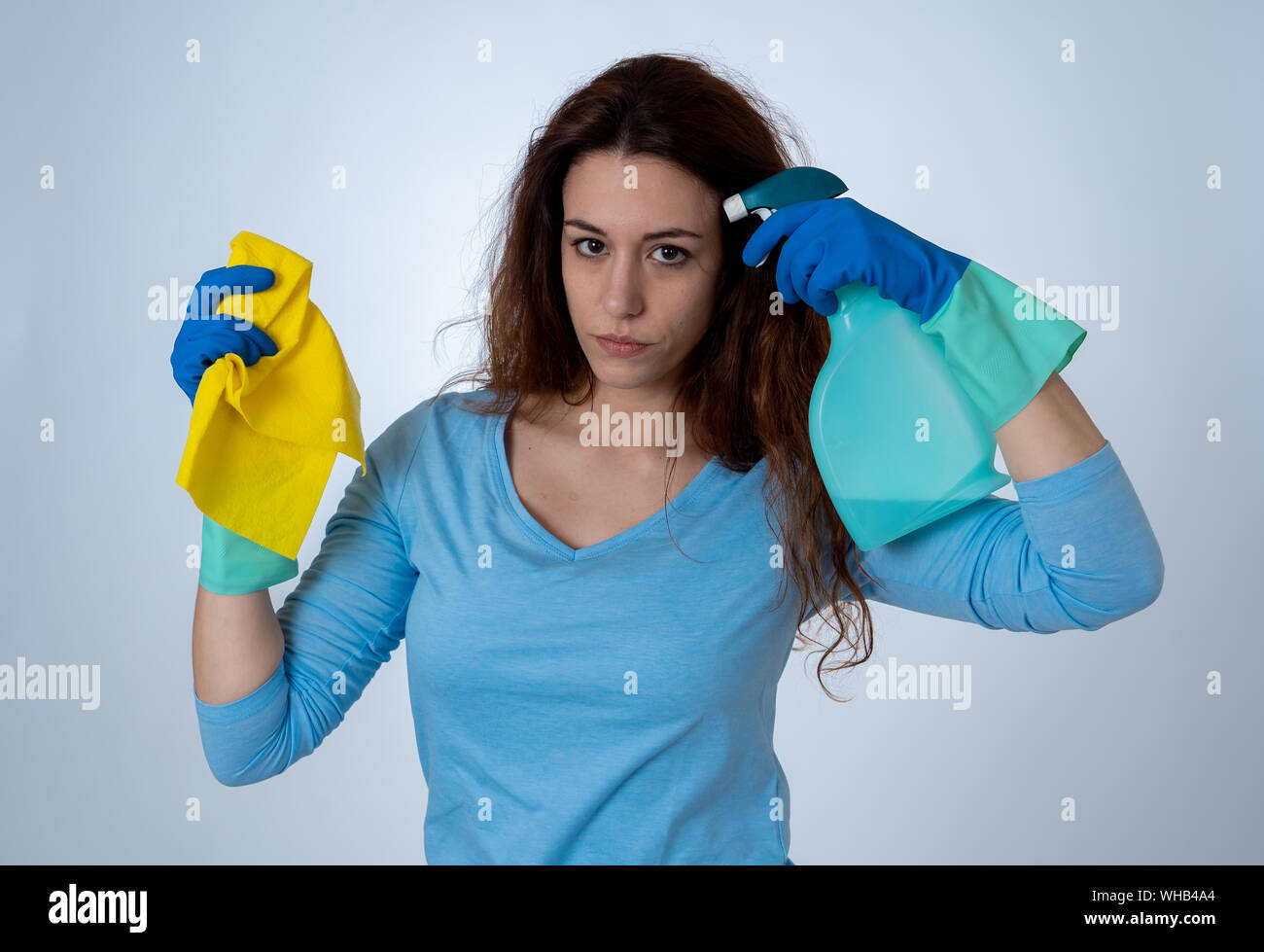 Beautiful angry and upset woman holding mop and cleaning spray feeling ...