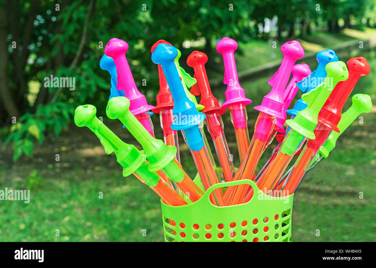 Toy soap bubbles in the shape of a sword stand in a green basket on a ...