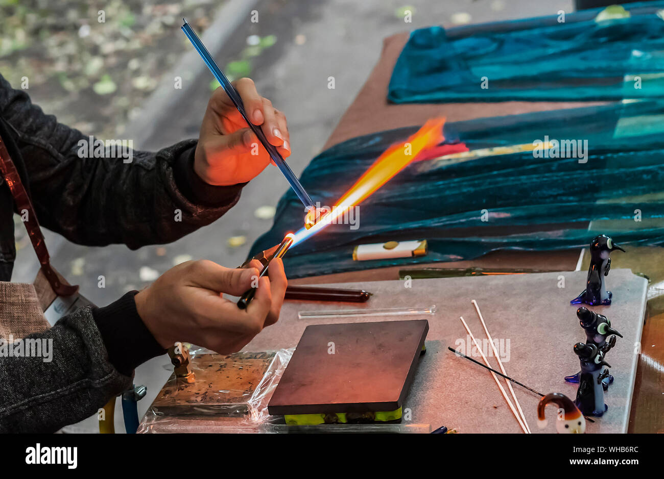 Glassblower makes a figurine of glass. Melting glass on a gas burner ...