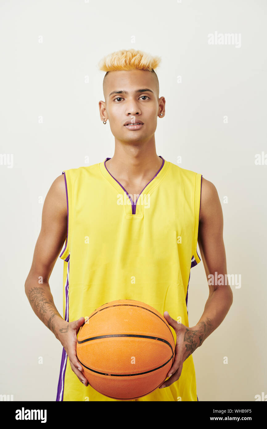 Portrait of handsome slim Black basketball player posing with ball ...