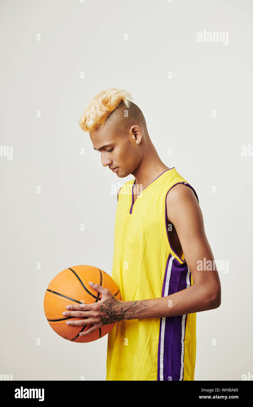 Pensive professional basketball player in bright yellow top looking at ...