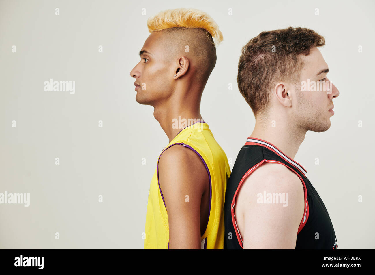 Serious young multi-ethnic basketball players in uniform staying back ...