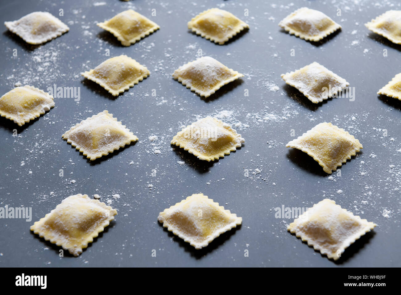 Fresh raw ravioli with flour on a dark background. Process of making ...