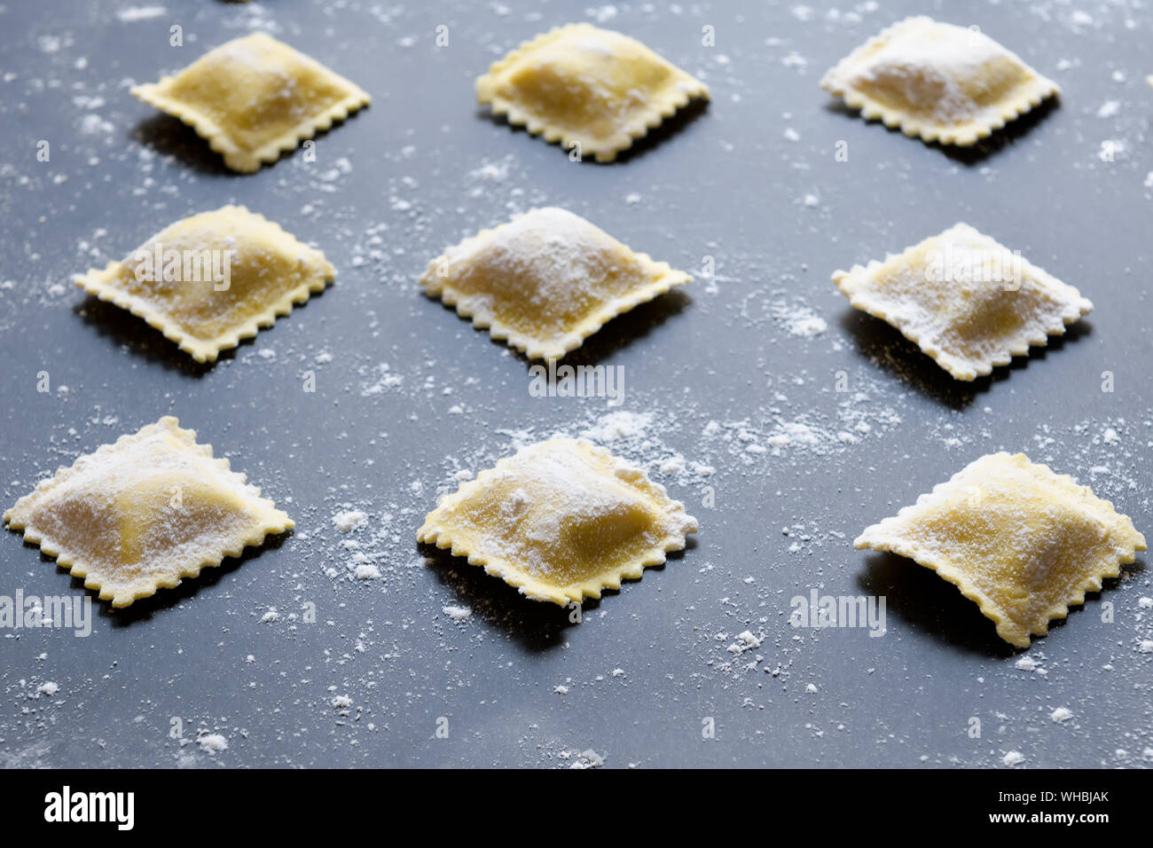 Fresh raw ravioli with flour on a dark background. Process of making ...