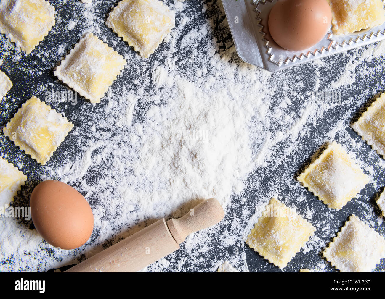 Fresh raw ravioli with flour on a dark background. Process of making ...