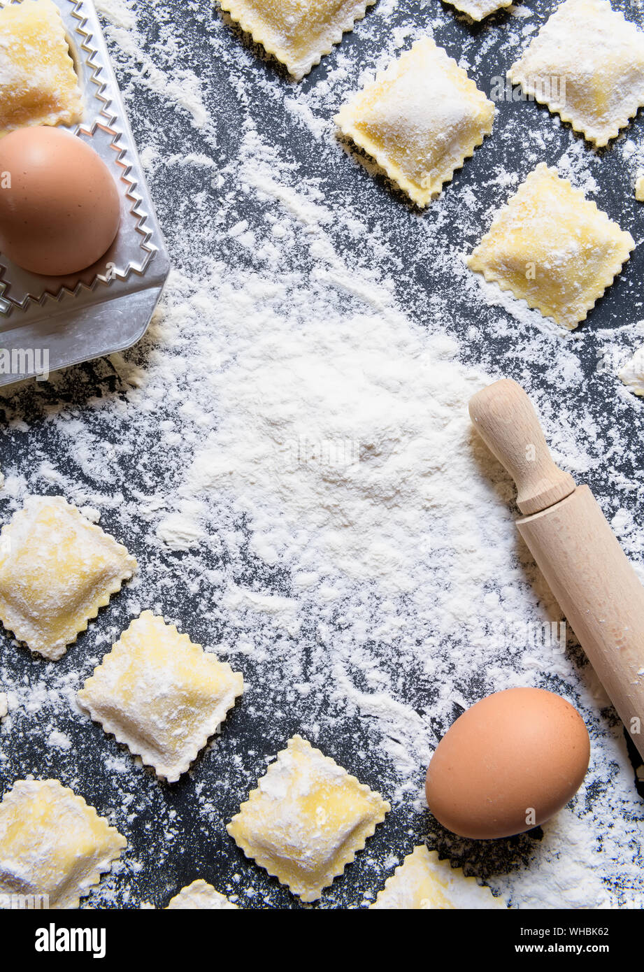Fresh raw ravioli with flour on a dark background. Process of making ...