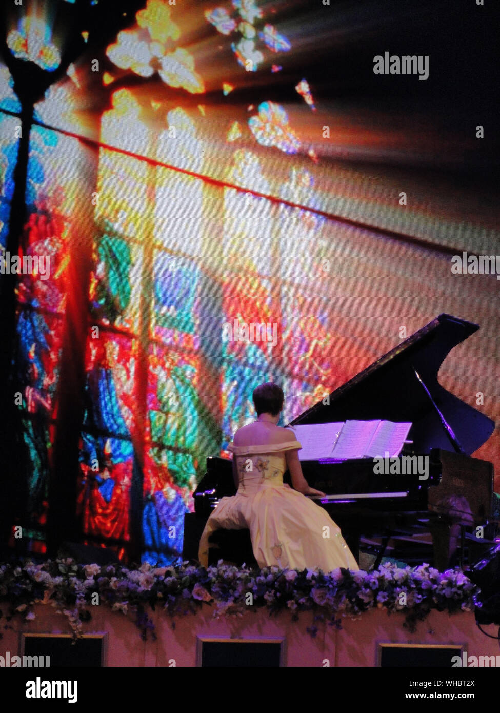 A portrait of a female pianist in a princess dress playing on the stage ...