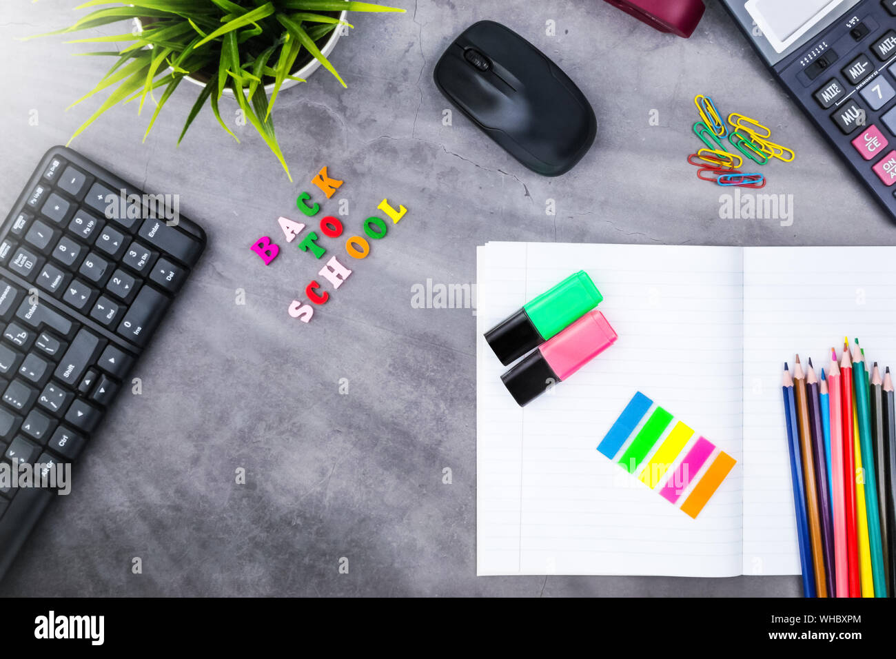 The layout of school supplies on a dark gray background. Top view, the ...