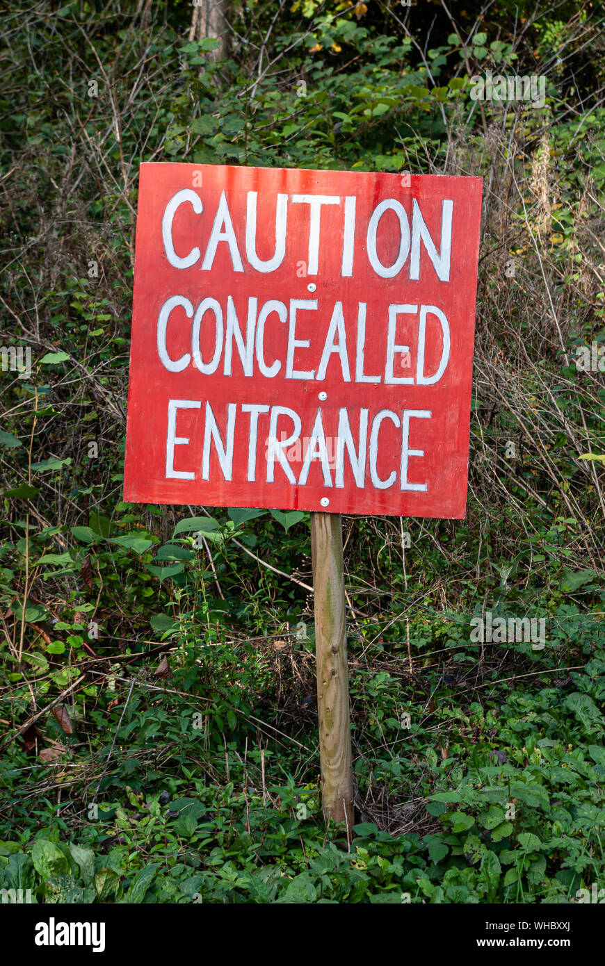 Hand-made 'Caution concealed entrance' sign with white writing on a red ...