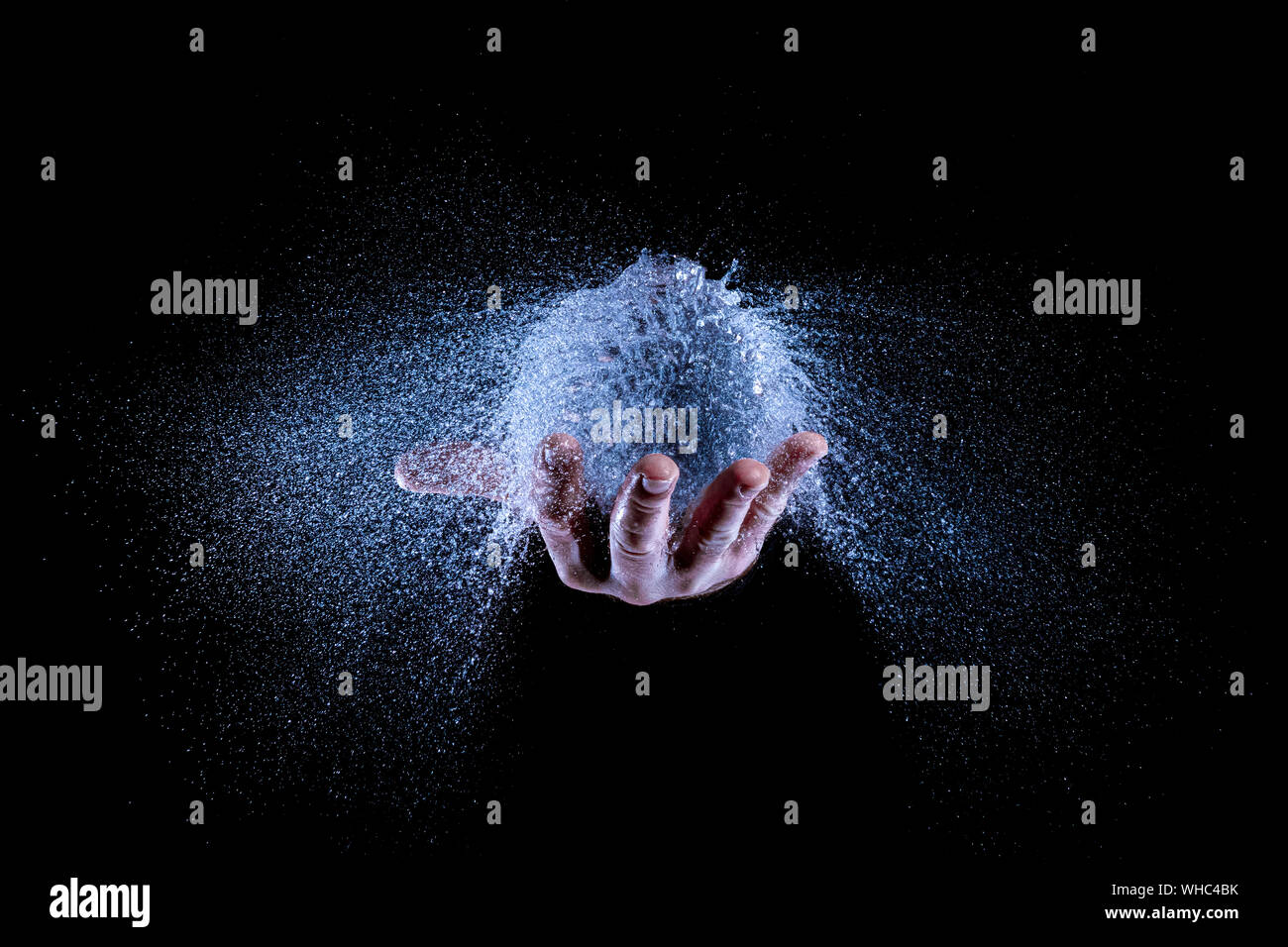 high speed photograph of an exploding balloon filled with water, hand ...