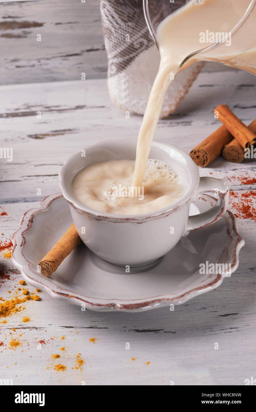 traditional indian masala chai tea pour on a beautiful cup ona shabby ...