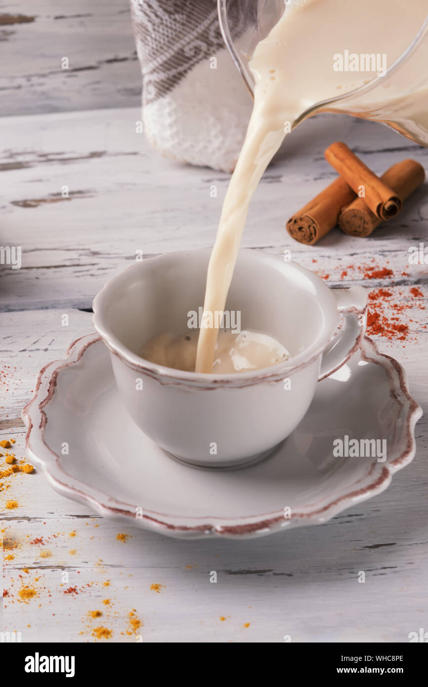 traditional indian masala chai tea pour on a beautiful cup ona shabby ...