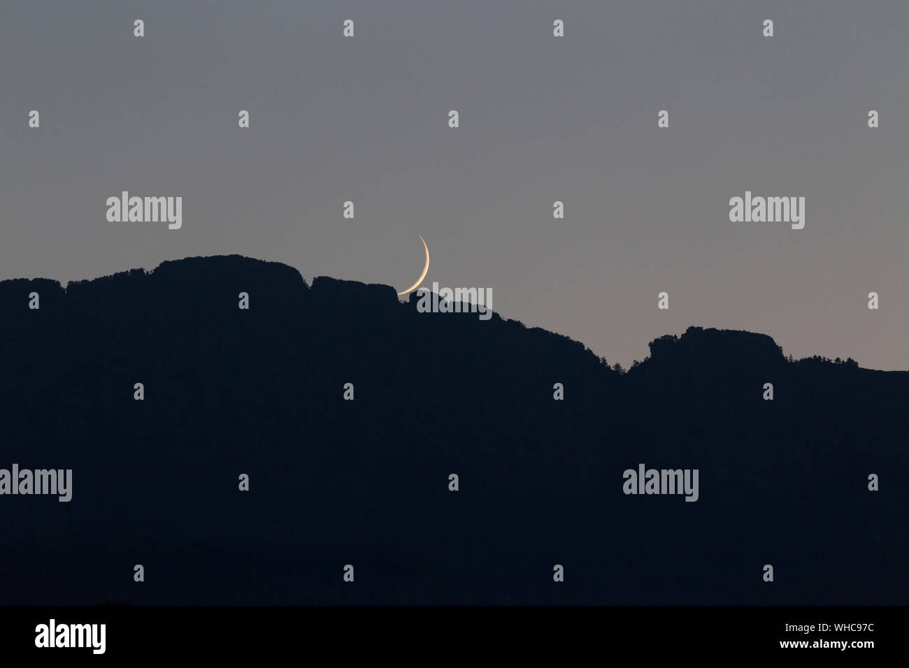 New moon rising over mountain ridge Stock Photo - Alamy