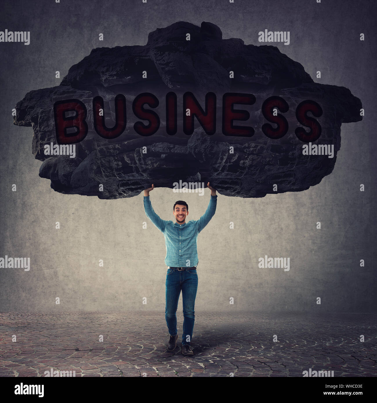 Strong businessman lifting up a huge heavy stone above his head as ...