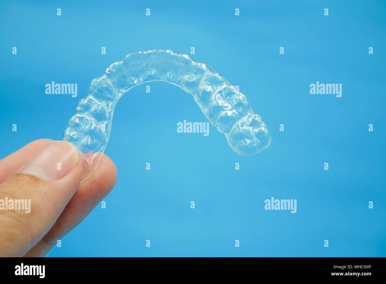 hand holding clear plastic retainer teeth that isolated on blue sky ...