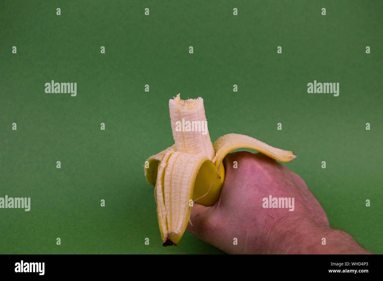 Yellow banana in a man's hand on a green background, there is free ...