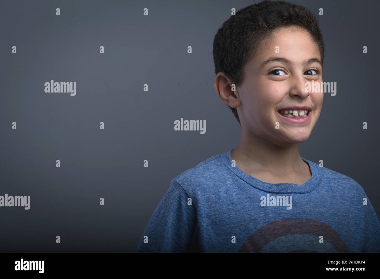 Portrait Of Smiling Boy Standing Against Gray Background Stock Photo ...