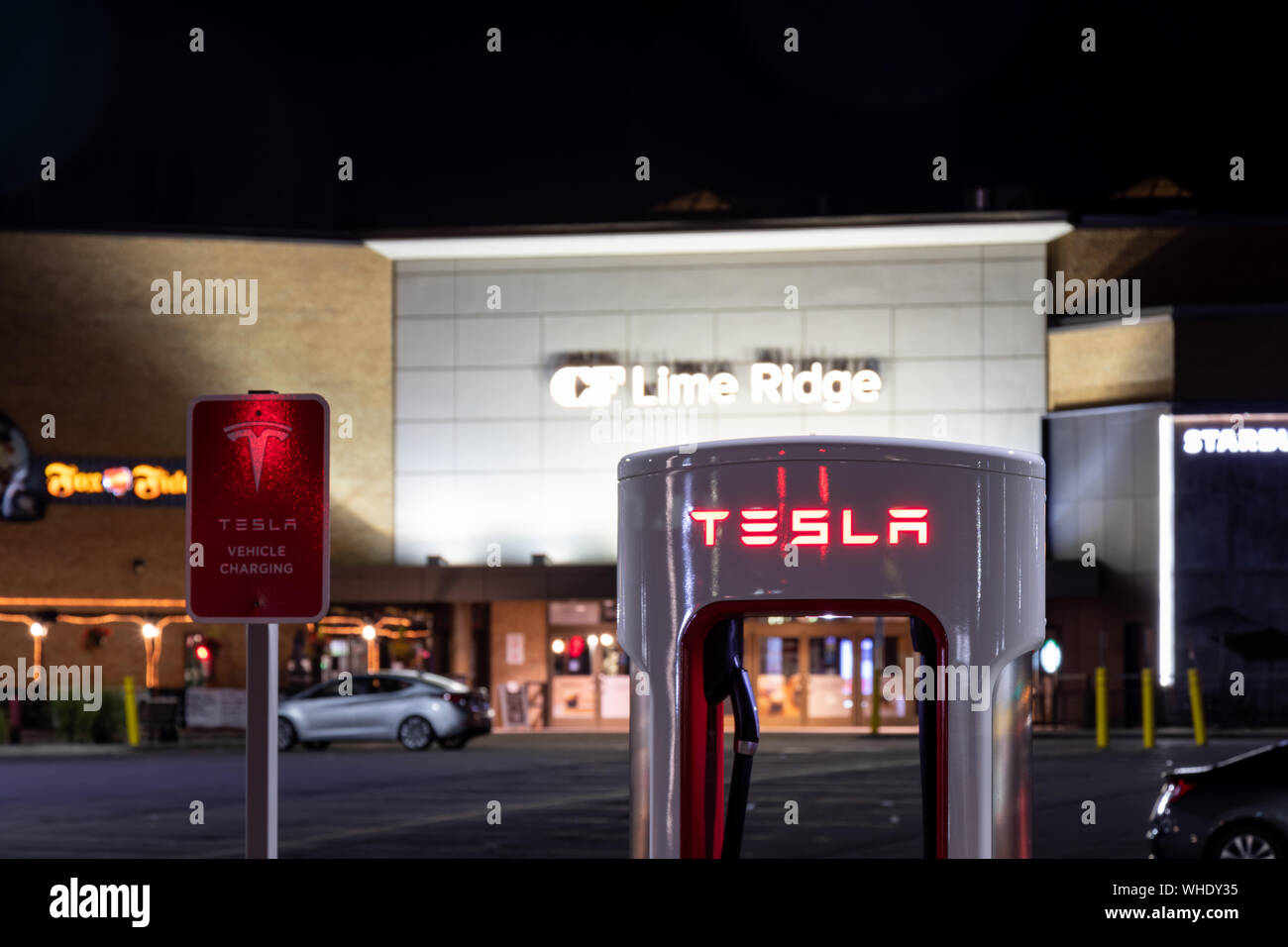 Tesla Supercharger with CF Lime Ridge entrance in view behind at night ...