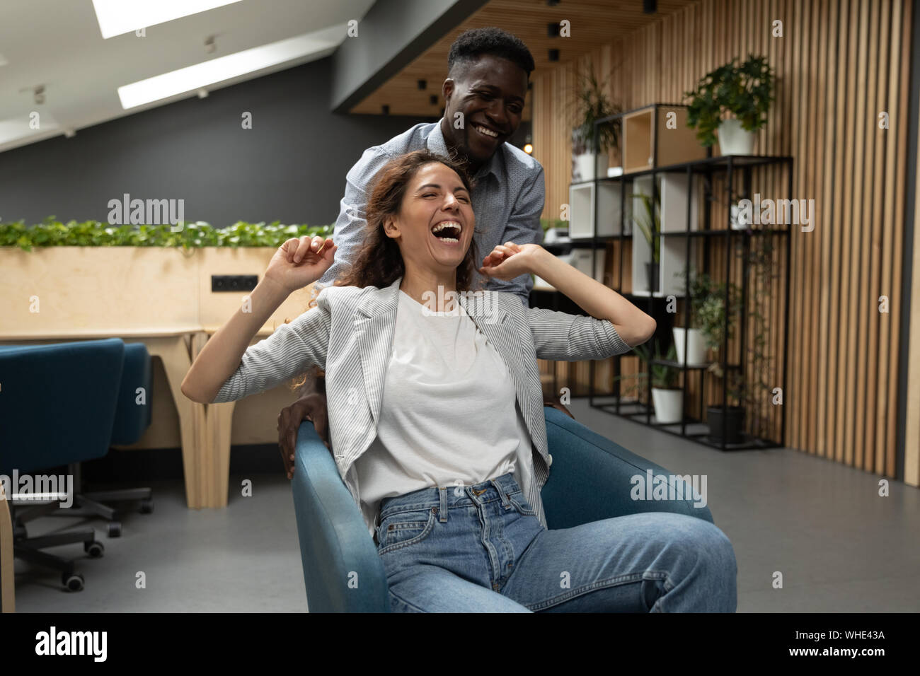 Happy diverse colleagues laughing riding on chair in office Stock Photo ...