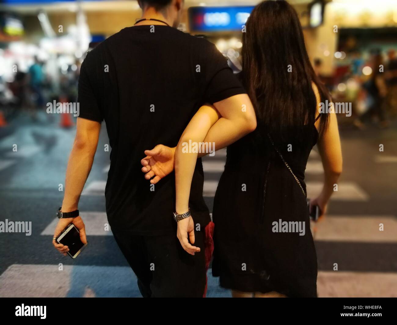 Rear View Of Couple With Arm Around Walking On Street Stock Photo - Alamy