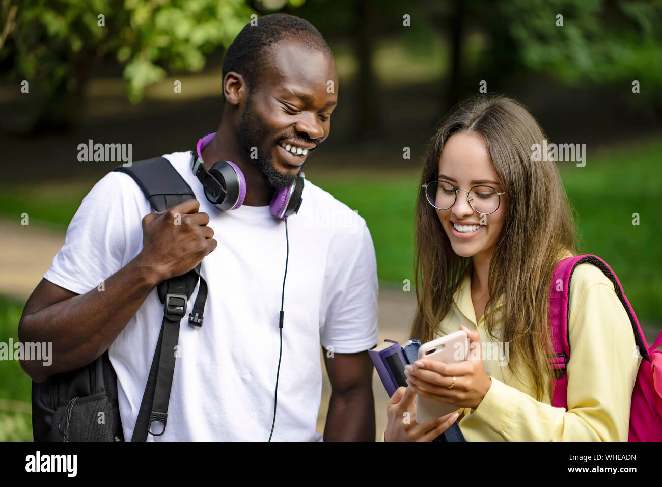 Cute Asian student girl shares something in her mobile phone with her ...