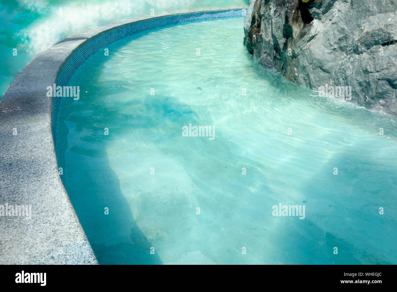Cyan water flow surrounded by rough rock or cliff and artificial ...