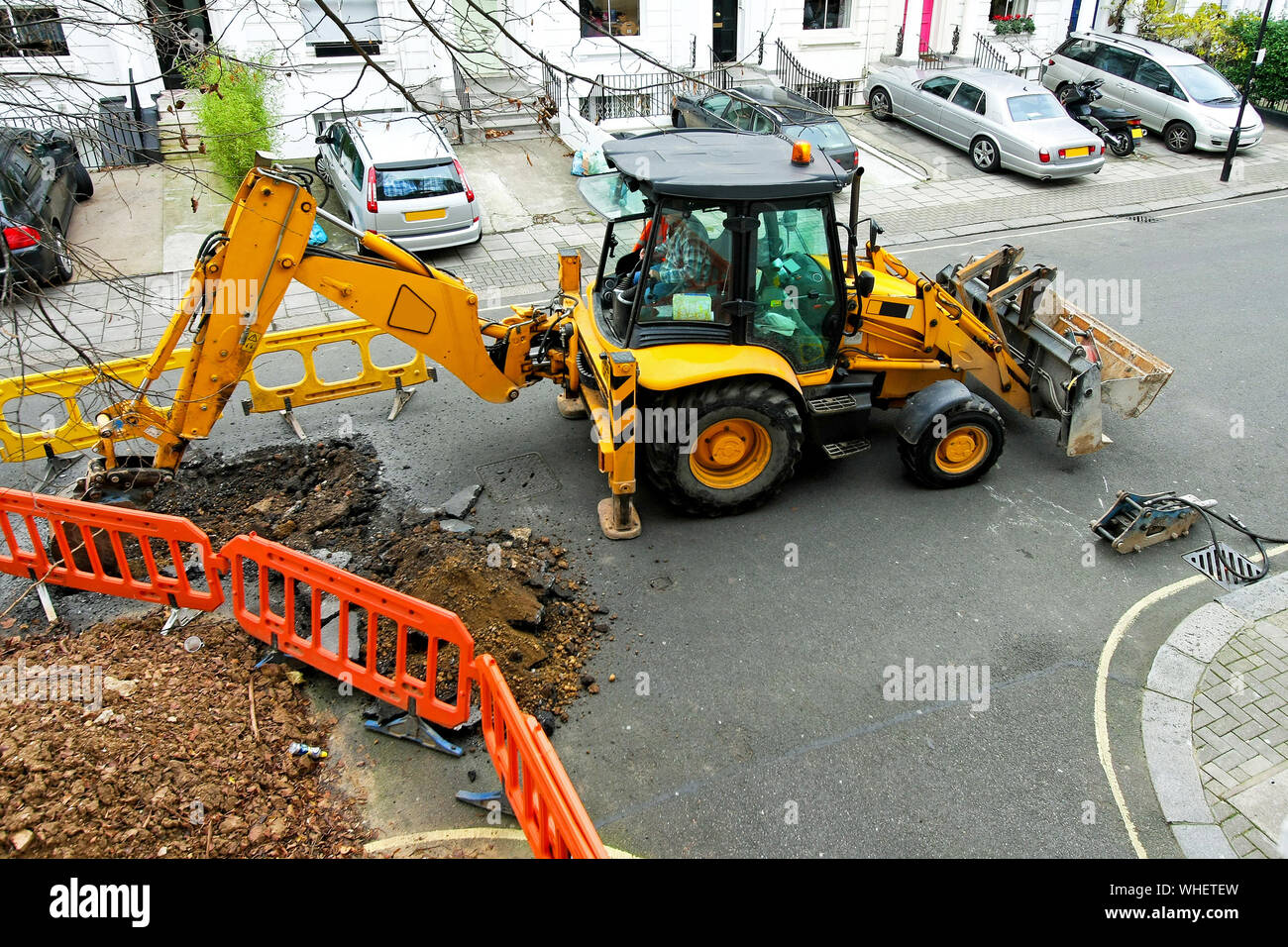 Contractor digging street with yellow excavator machine Stock Photo - Alamy