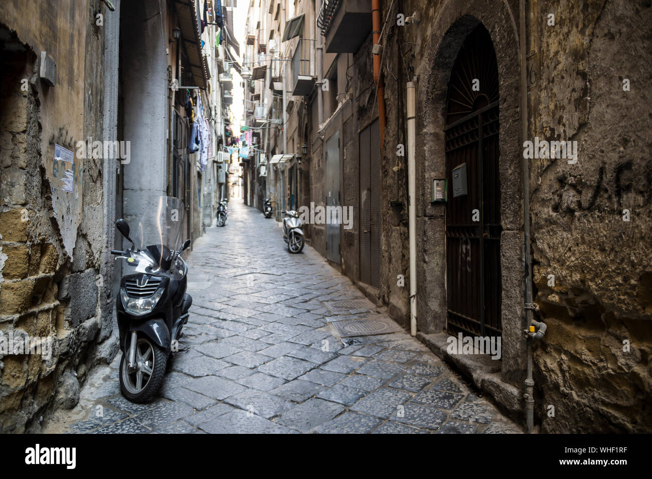 Scenic view of typical narrow alleyway lined with scooters and laundry ...