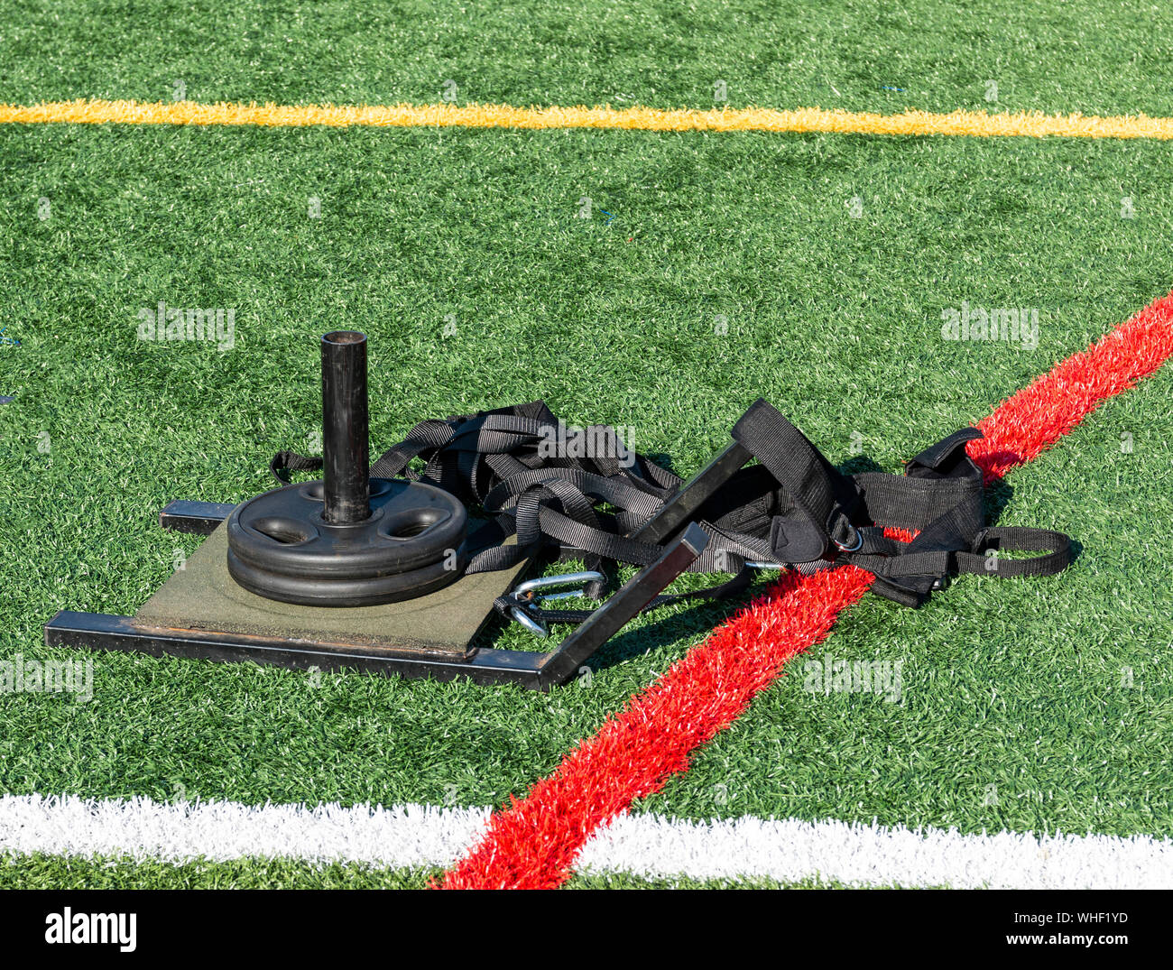 A pull sled is on a turf field with two twenty five pound weights ready ...
