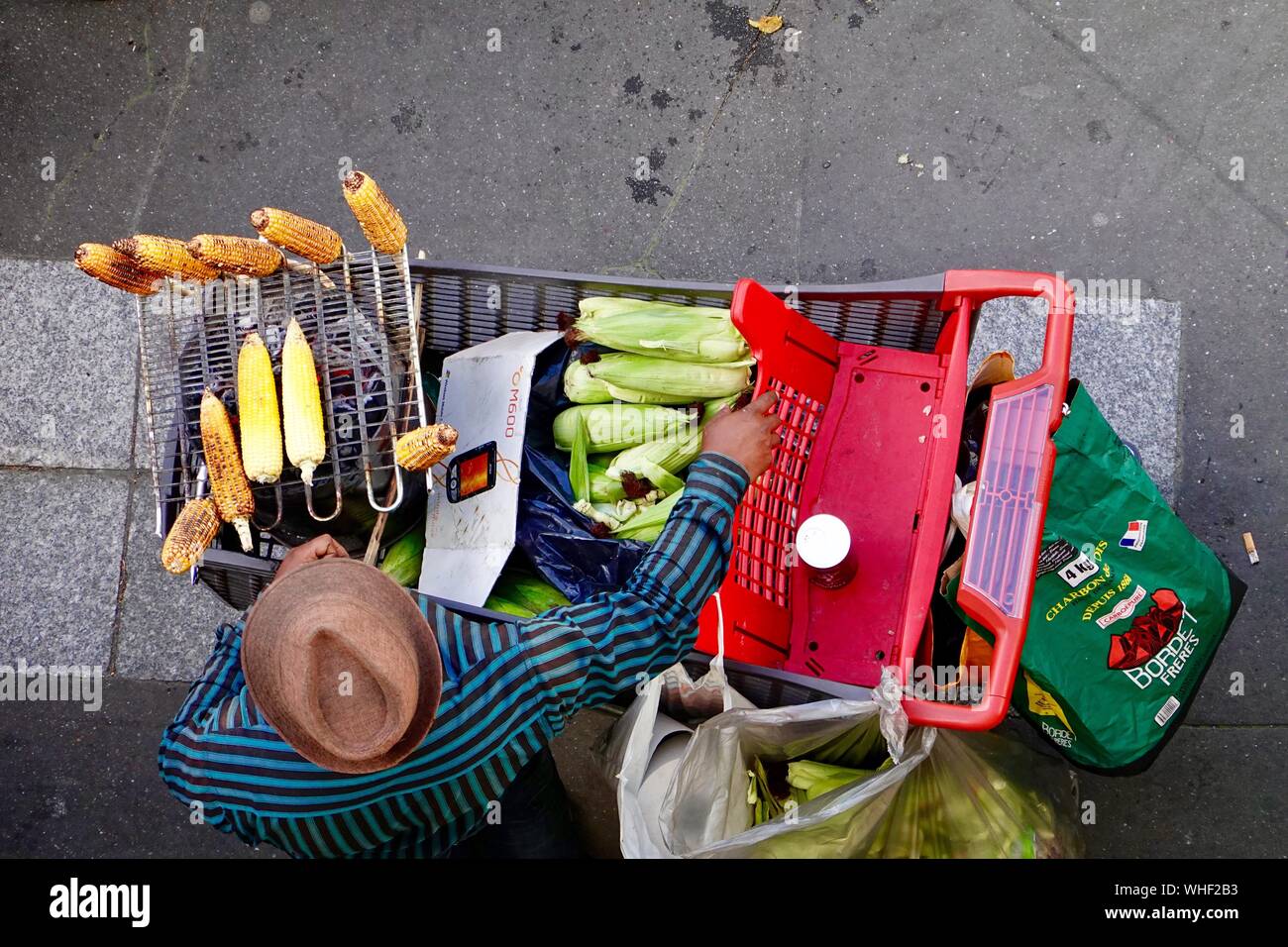 Man preparing corn on the cob to sell, with charcoal brazier on ...