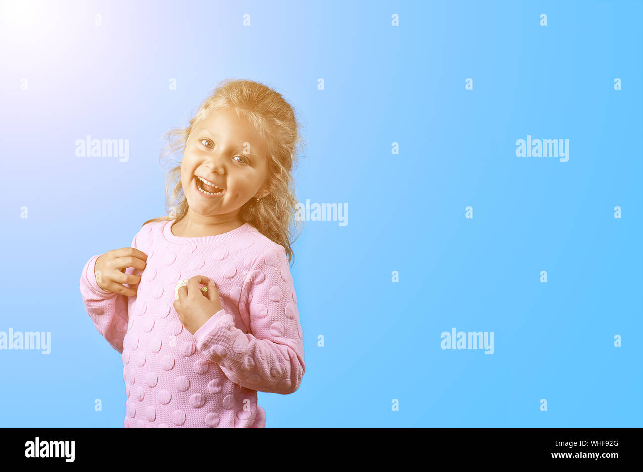A cute cheerful girl with dimples on her cheeks and curly hair smiles ...