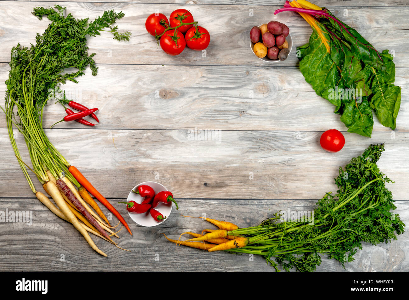 Wood table with a selection of fresh vegetables arranged to form a ...
