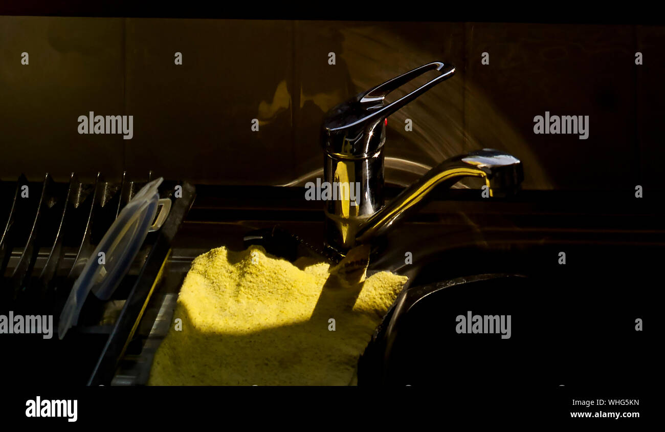 Abstract of faucet (tap) and yellow kitchen towel on kitchen worktop ...