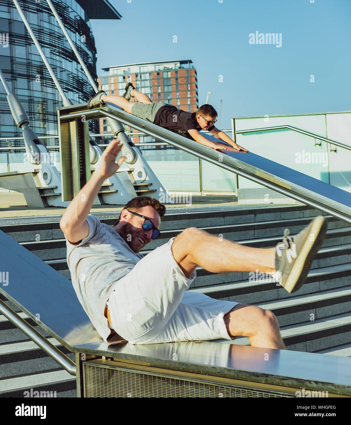 Man and Child slide down railings outside Stock Photo - Alamy
