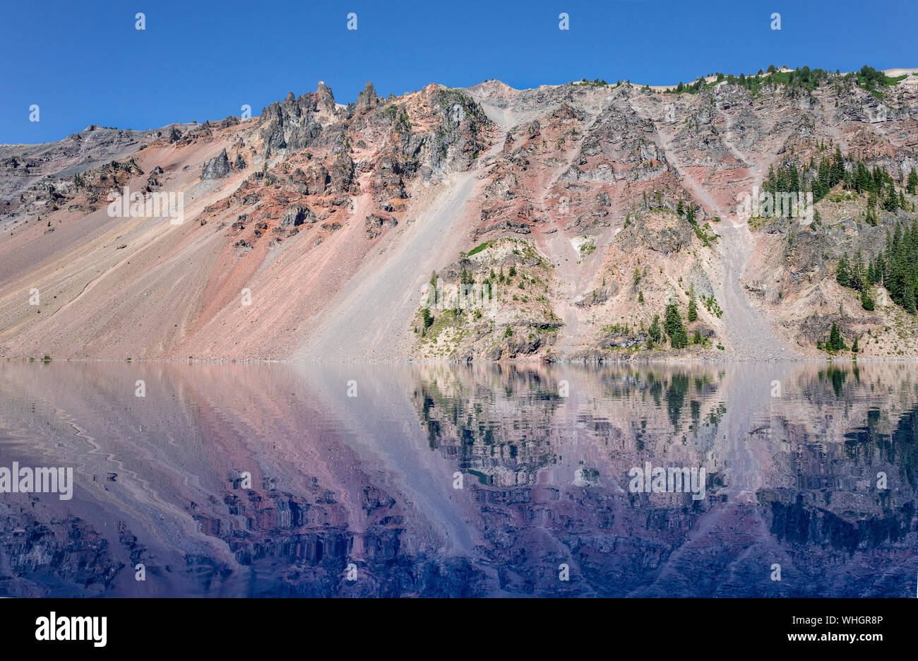 A view of Crater Lake rim reflected in its waters. The rim is doted by ...