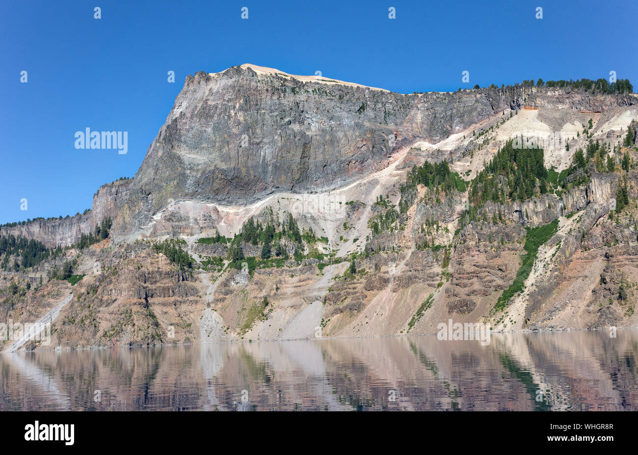 A view of Crater Lake rim reflected in its waters. The rim is doted by ...